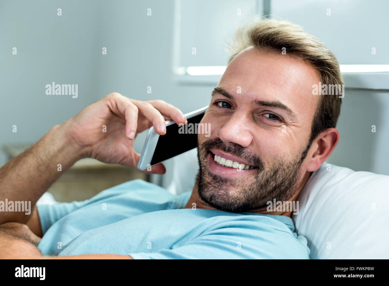 Portrait of man talking on mobile phone while relaxing on bed Stock ...