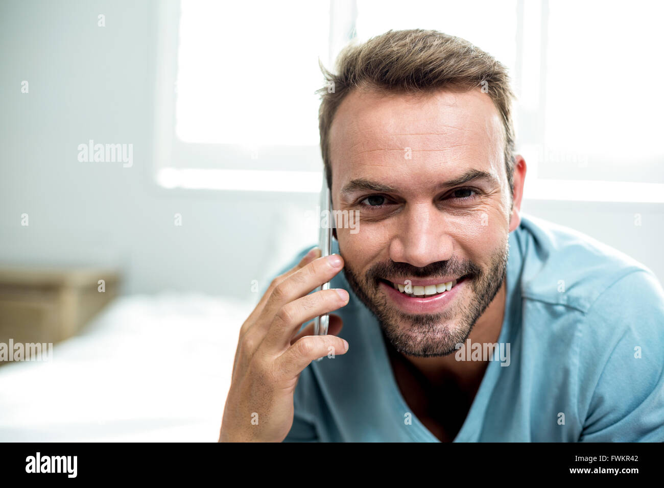 Portrait of happy man using cellphone on bed Stock Photo - Alamy