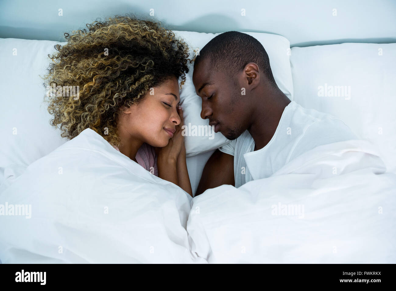 Young couple sleeping face to face on bed Stock Photo - Alamy