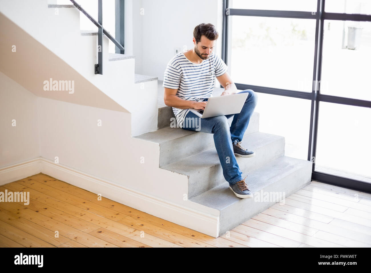 Happy man sitting on steps using laptop Stock Photo - Alamy