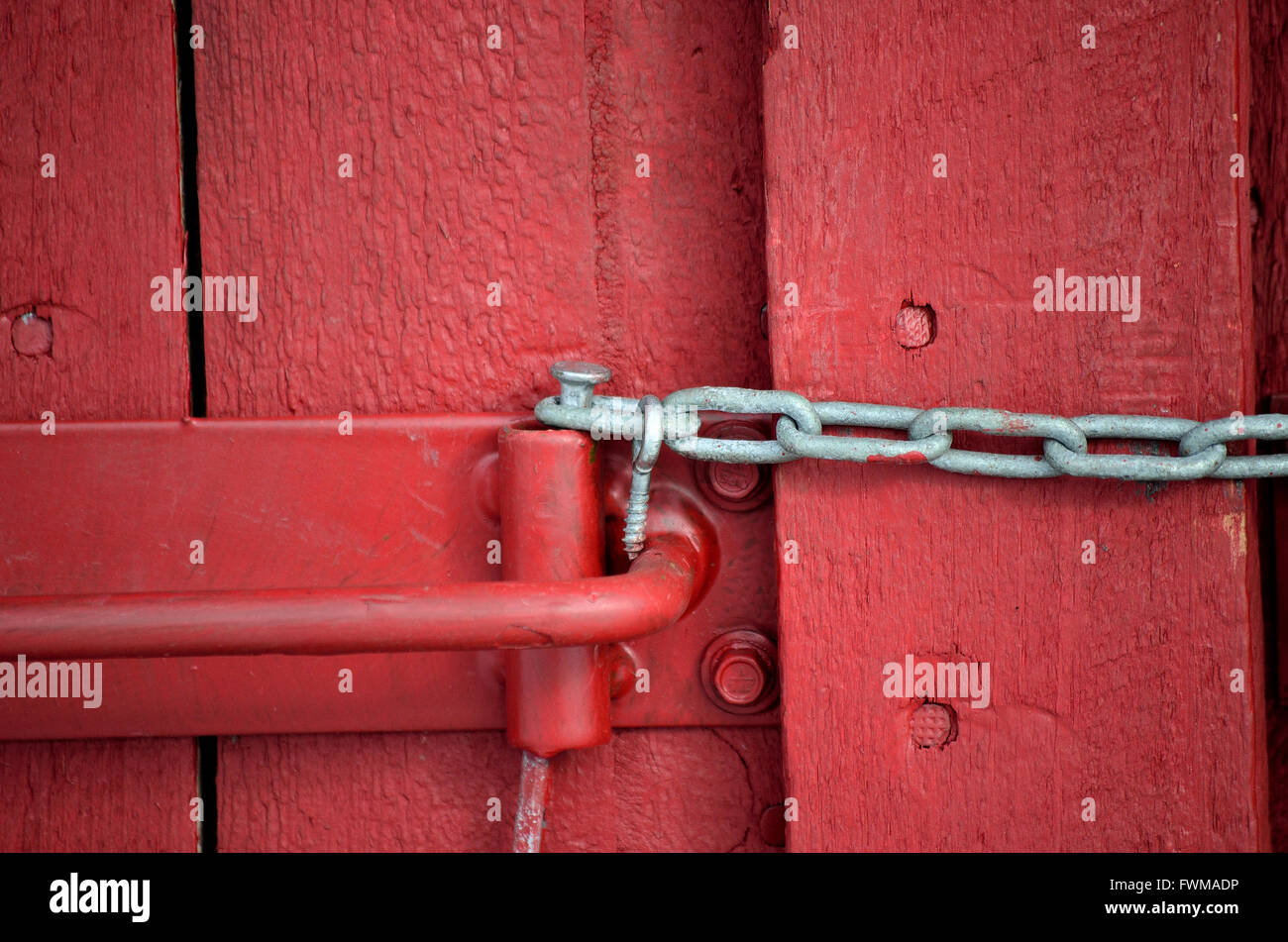red barn door with metal chain and screw lock homemade Stock Photo - Alamy
