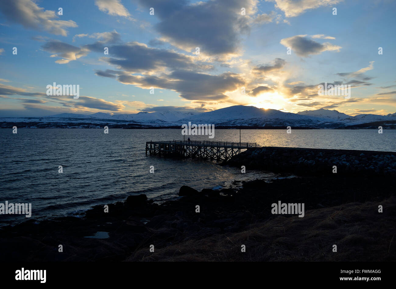 beautiful sunset over snowy mountain, fjord and pier Stock Photo - Alamy