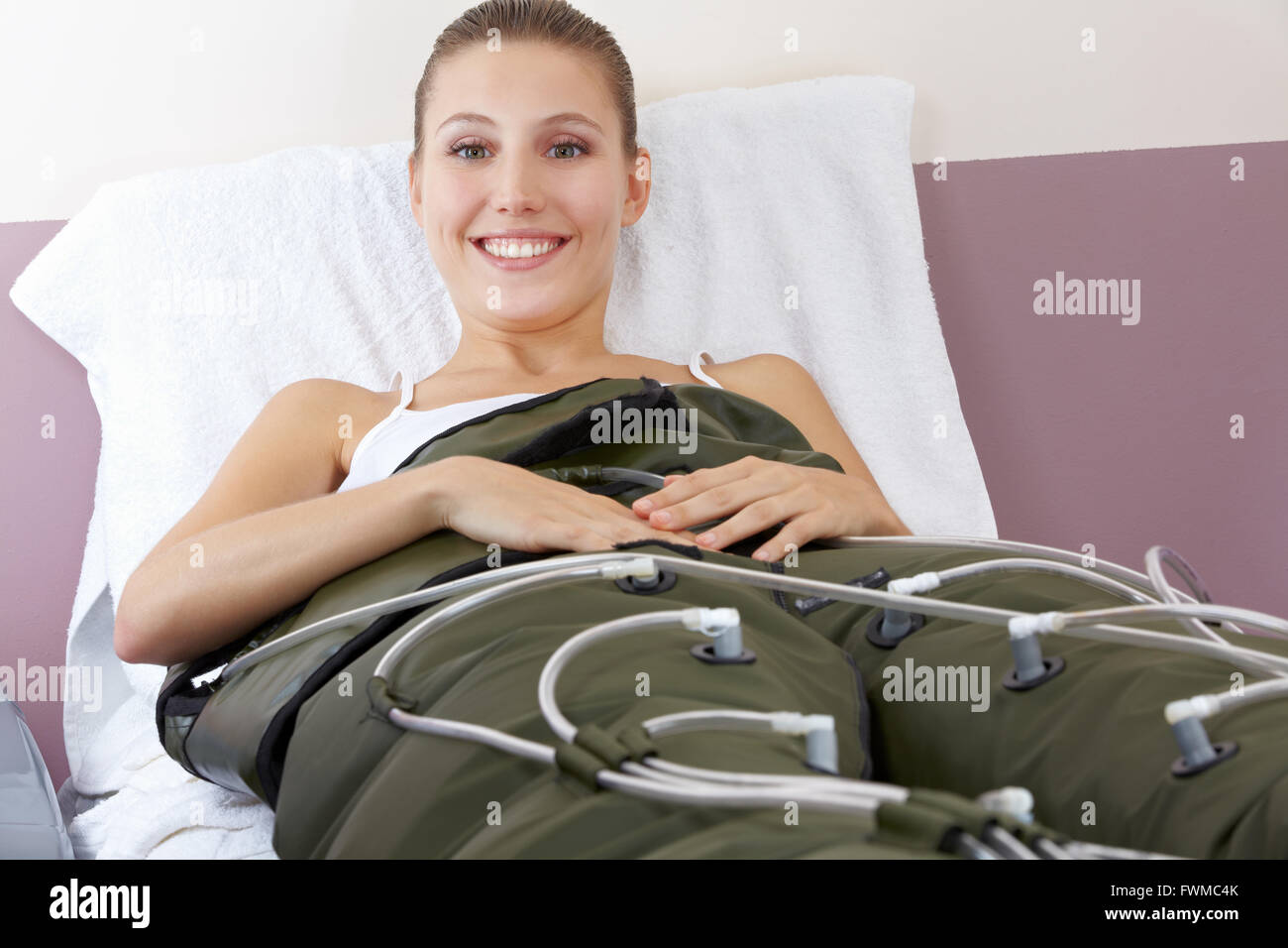 Happy woman getting pressure wave massage for skin tightening in spa ...