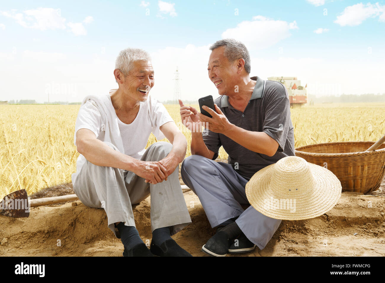 Two farmers sitting in field talking Stock Photo - Alamy