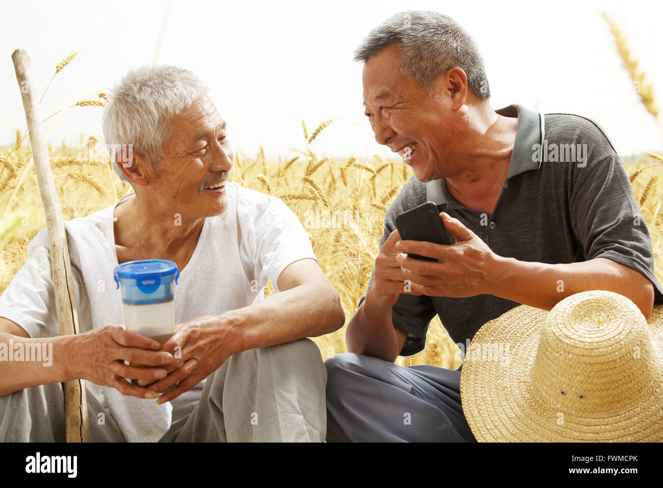 Two farmers sitting in field talking Stock Photo - Alamy