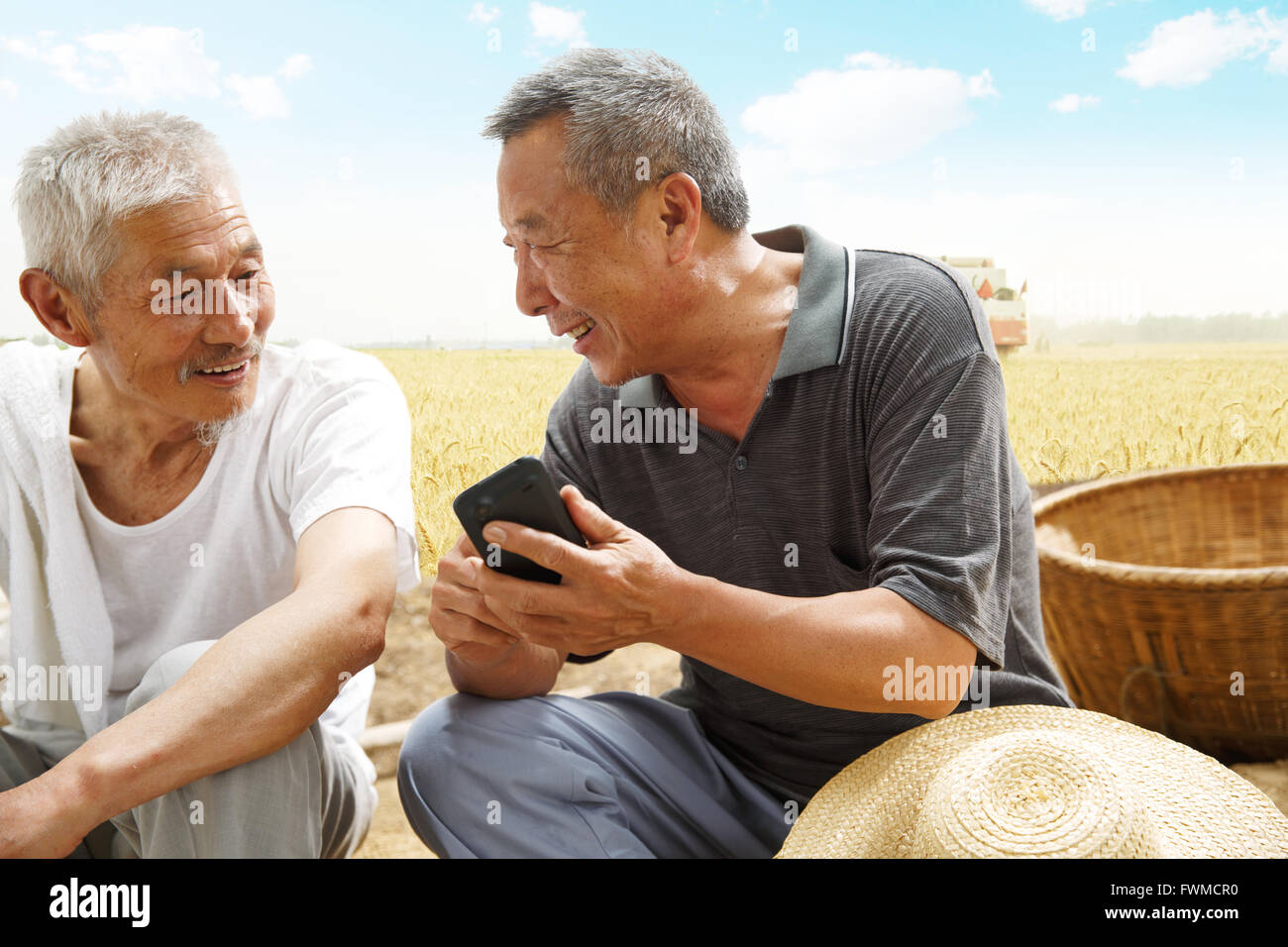 Two farmers sitting in field talking Stock Photo - Alamy
