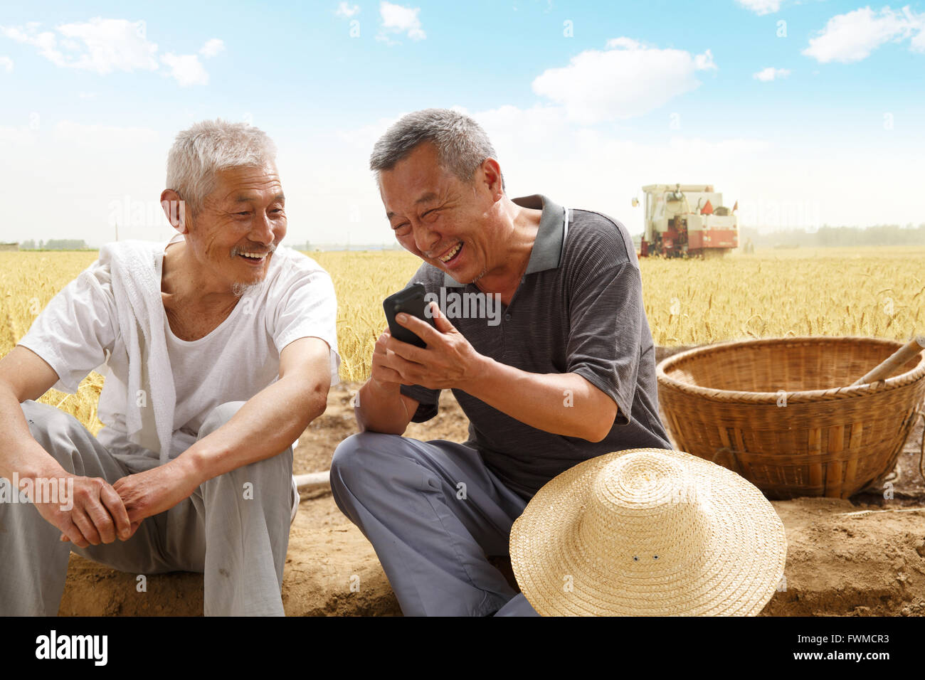 Two farmers sitting in field talking Stock Photo - Alamy