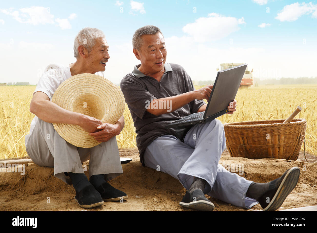 Two farmers sitting in field talking Stock Photo - Alamy