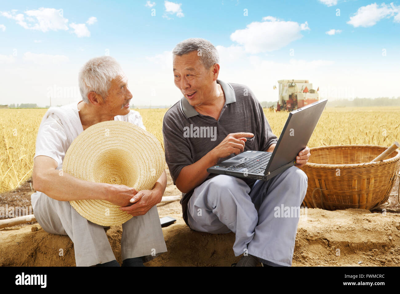 Two farmers sitting in field talking Stock Photo - Alamy