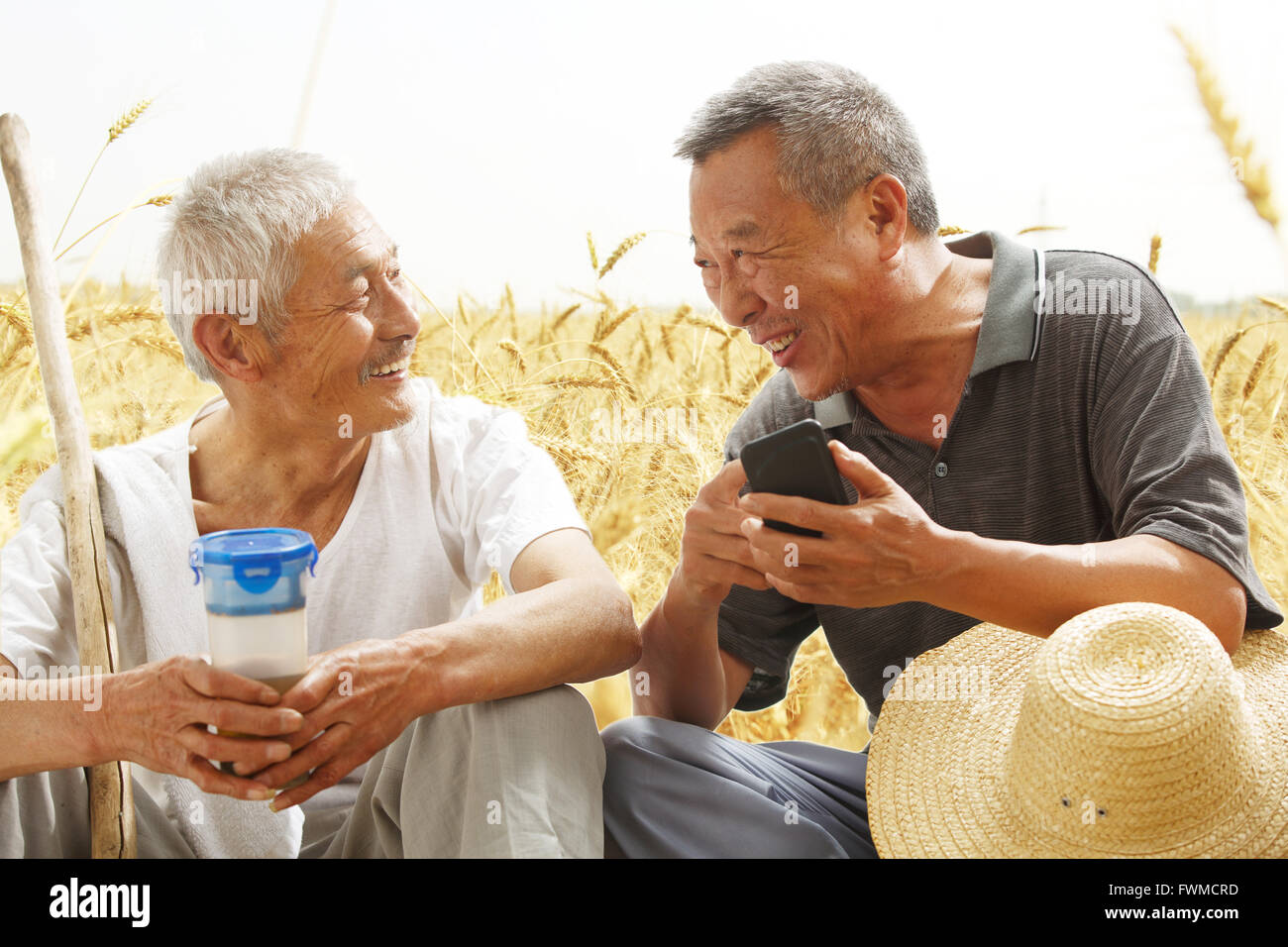 Two farmers sitting in field talking Stock Photo - Alamy