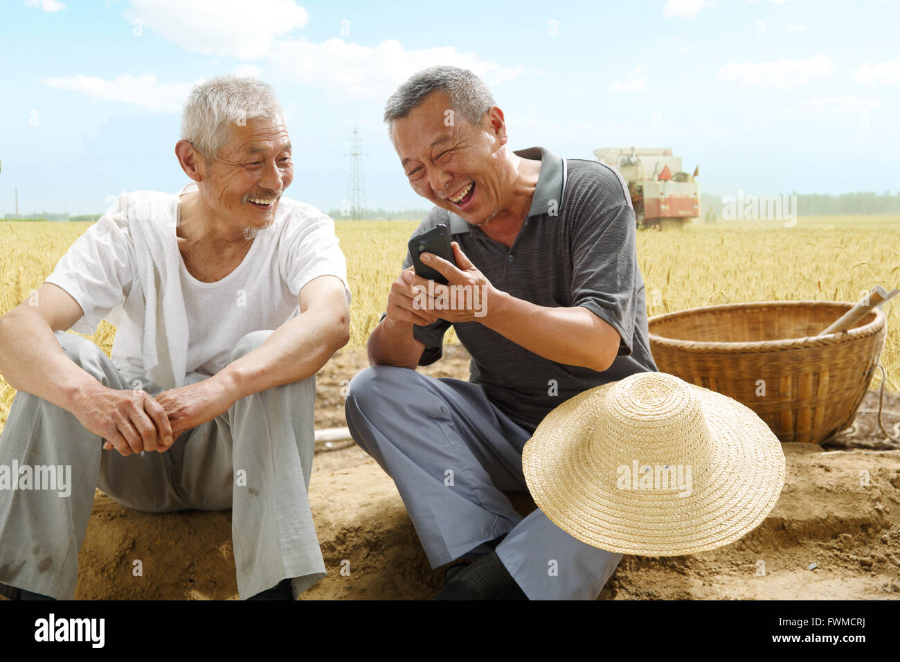 Two farmers sitting in field talking Stock Photo - Alamy