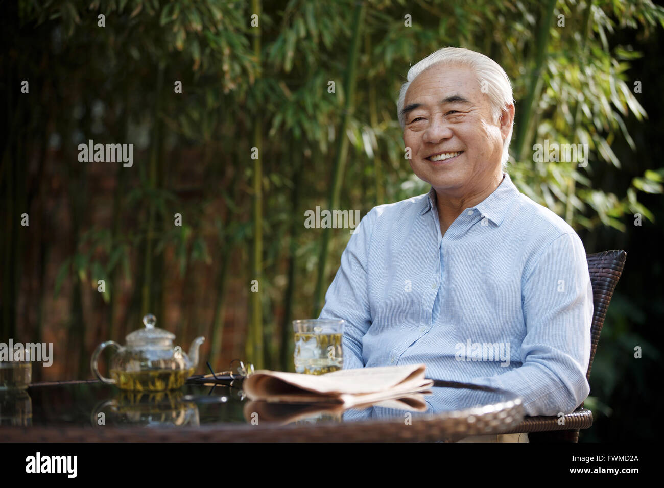 Senior man sitting in yard drinking tea Stock Photo - Alamy