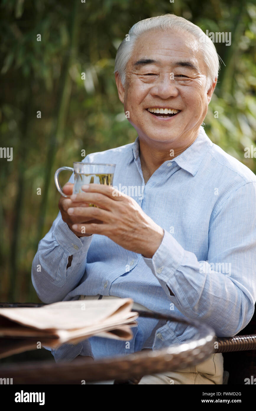 Senior man sitting in yard drinking tea Stock Photo - Alamy