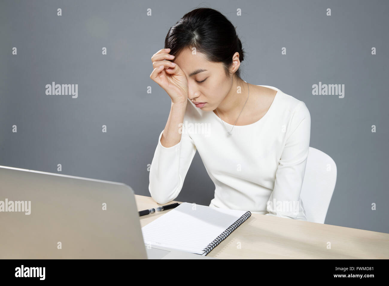 Fatigue young woman sitting at a table Stock Photo - Alamy