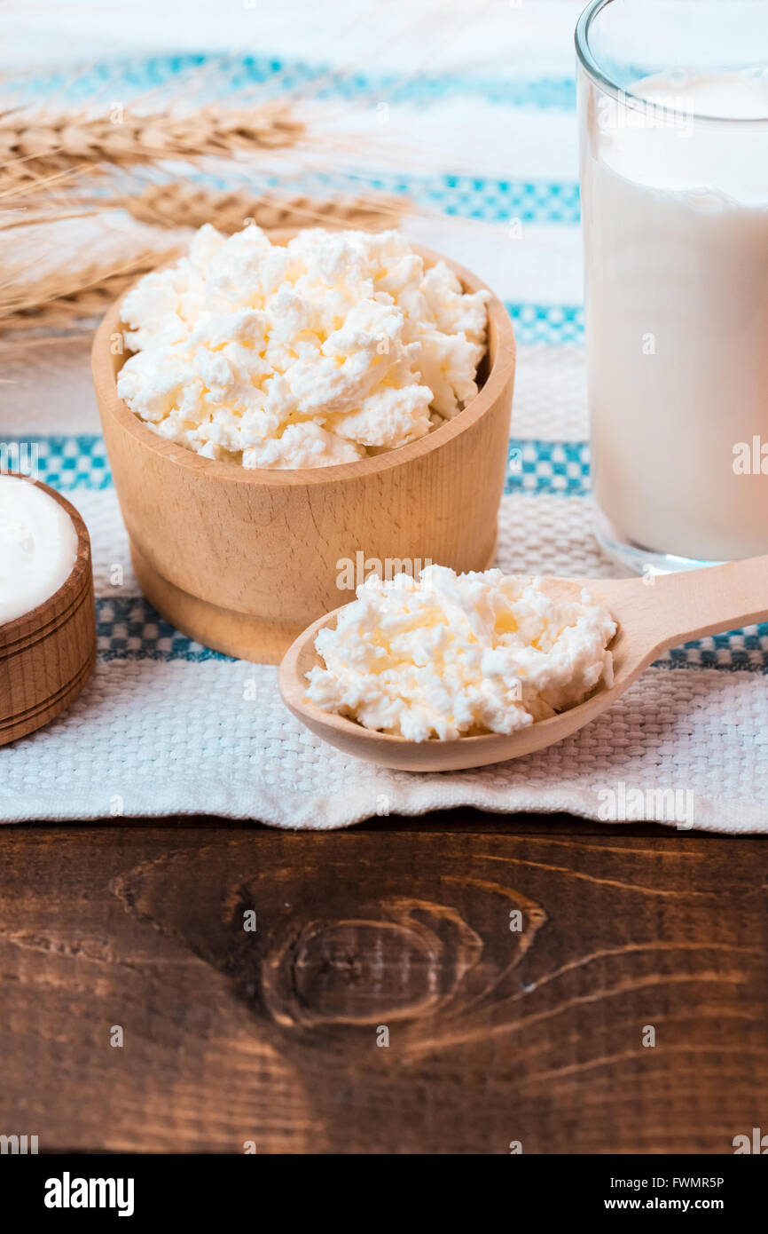 Cottage cheese, glass of milk, two eggs, wooden spoon with cottage ...
