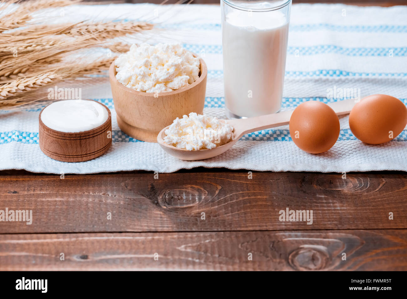 Cottage cheese, glass of milk, two eggs, wooden spoon with cottage ...