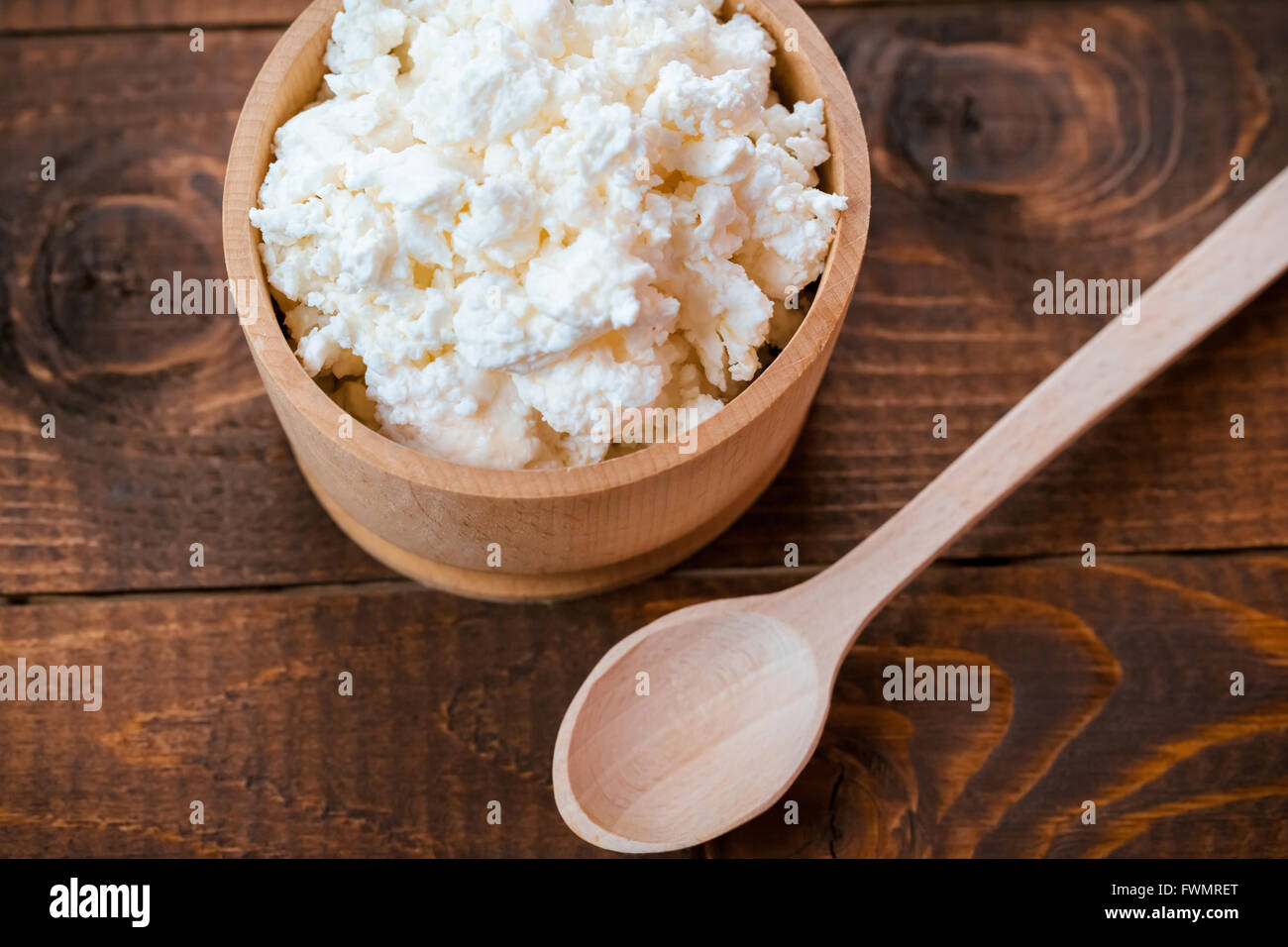 Natural homemade curd in wooden bowl with wooden spoon on brown boards ...
