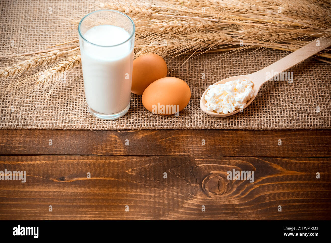 Cottage cheese, glass of milk, two eggs, wooden spoon with cottage ...