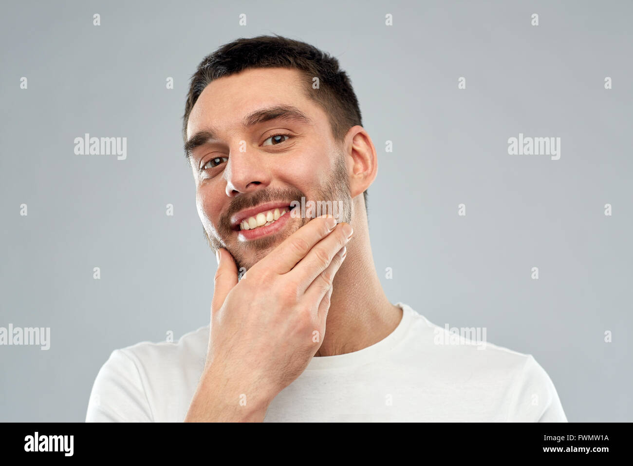 happy young man touching his face or beard Stock Photo - Alamy