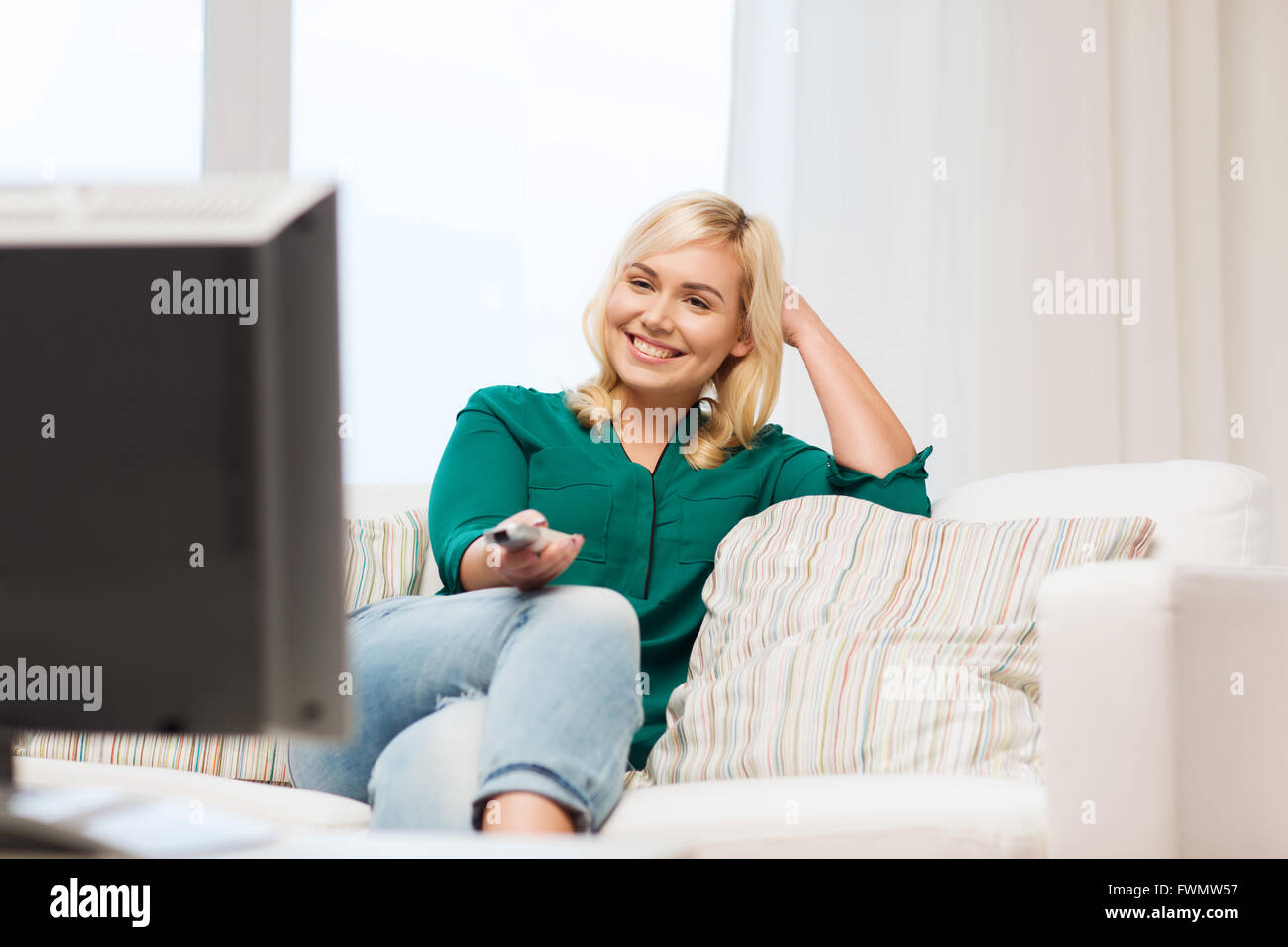 smiling woman with remote watching tv at home Stock Photo - Alamy