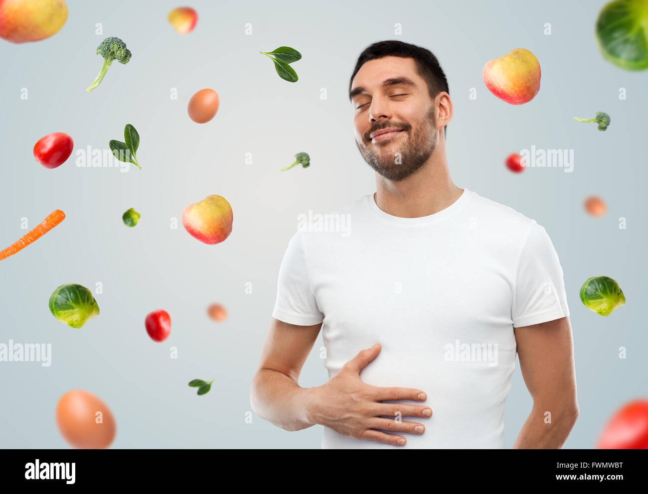 happy full man touching tummy over falling fruits Stock Photo - Alamy