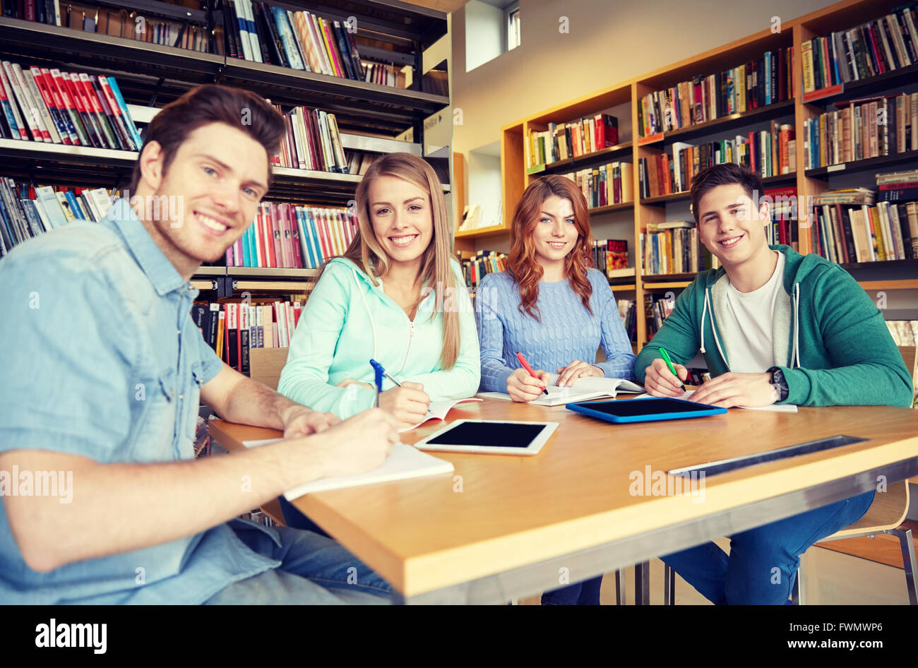 happy students writing to notebooks in library Stock Photo - Alamy