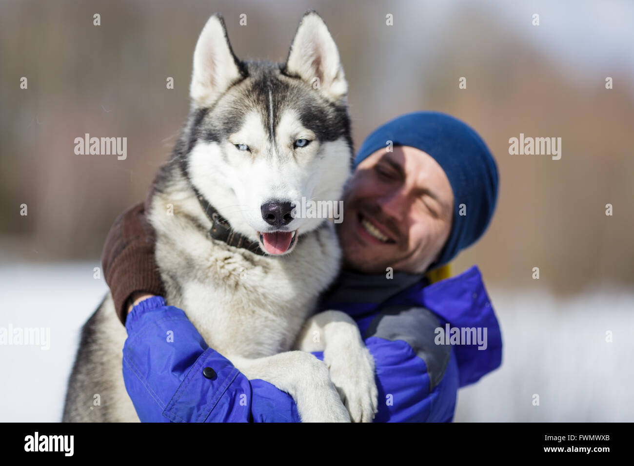 Happy man with a husky at winter time Stock Photo - Alamy