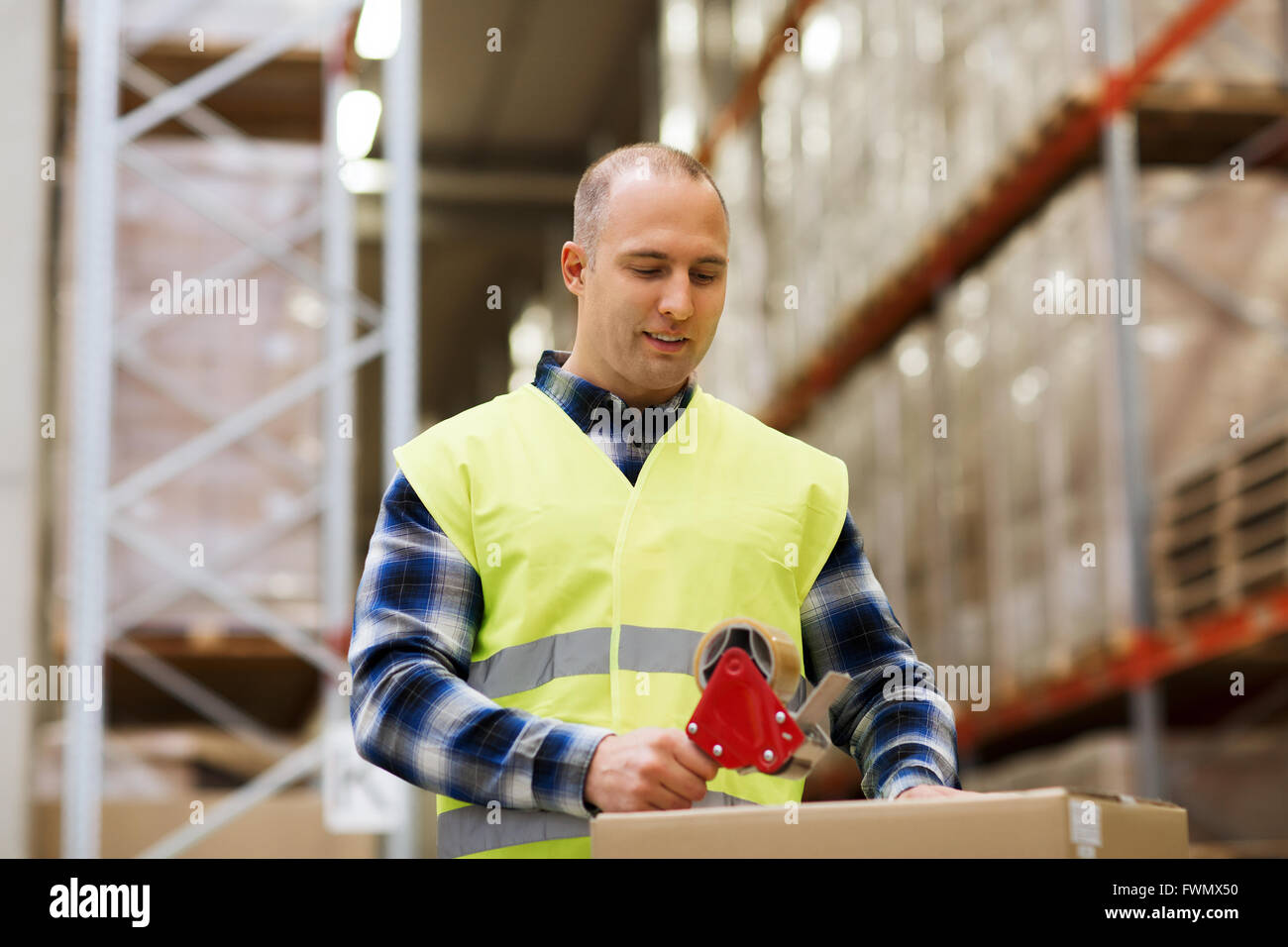 man in safety vest packing box at warehouse Stock Photo - Alamy