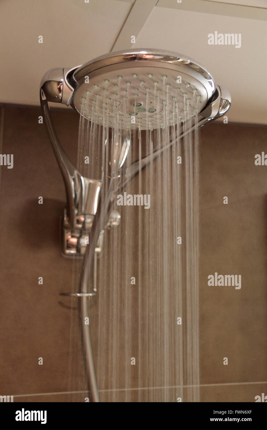 A large spray shower head with running water in a hotel bathroom in the ...