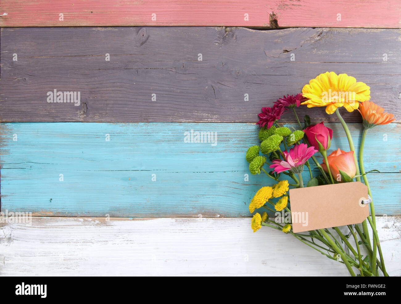 Bunch of flowers with blank gift label on wooden background Stock Photo ...