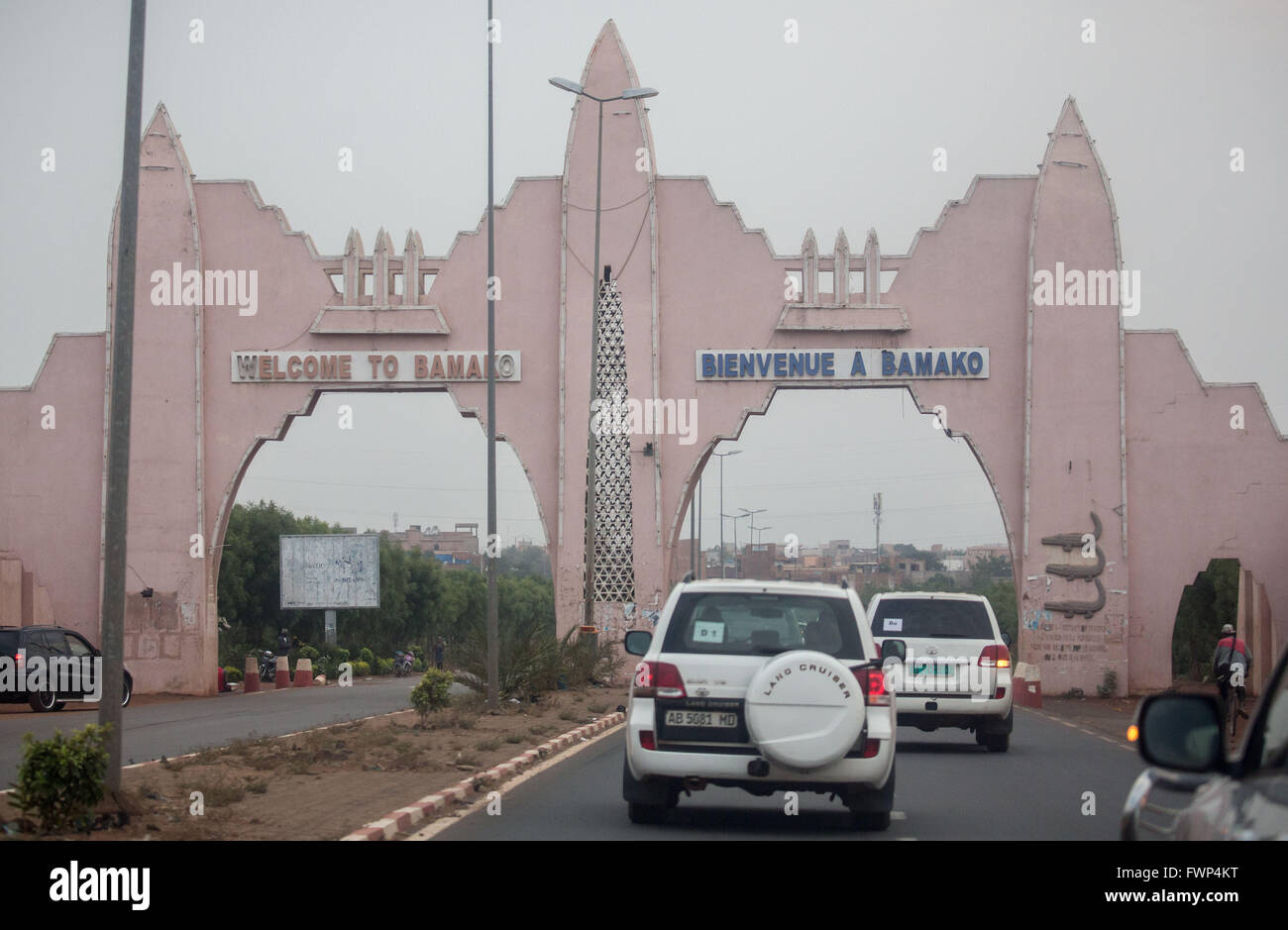 Cars pass through the city gate of Bamako that reads 'Bienvenue a ...