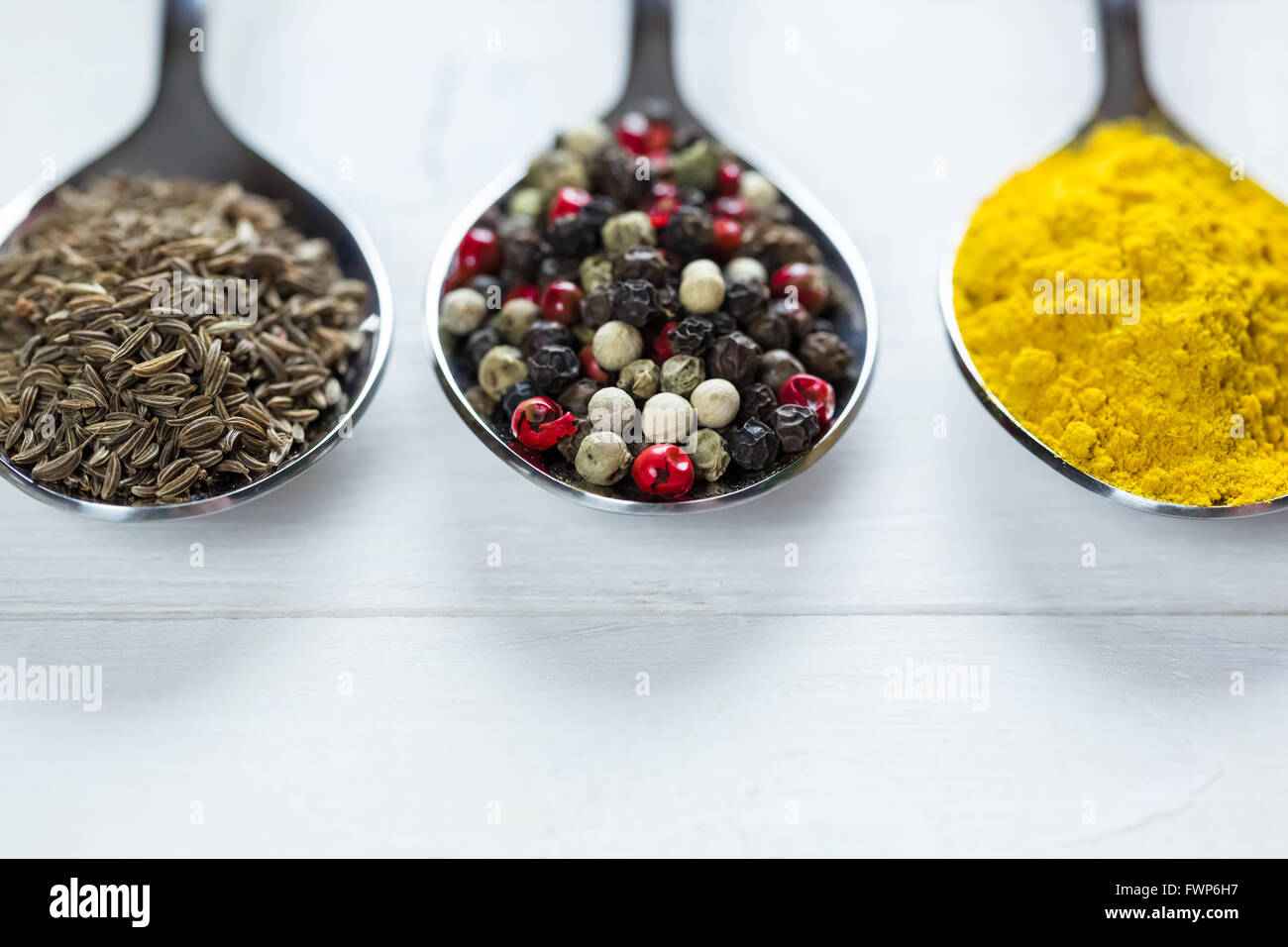 Beautiful colorful spices in an iron spoon on old wooden table white ...