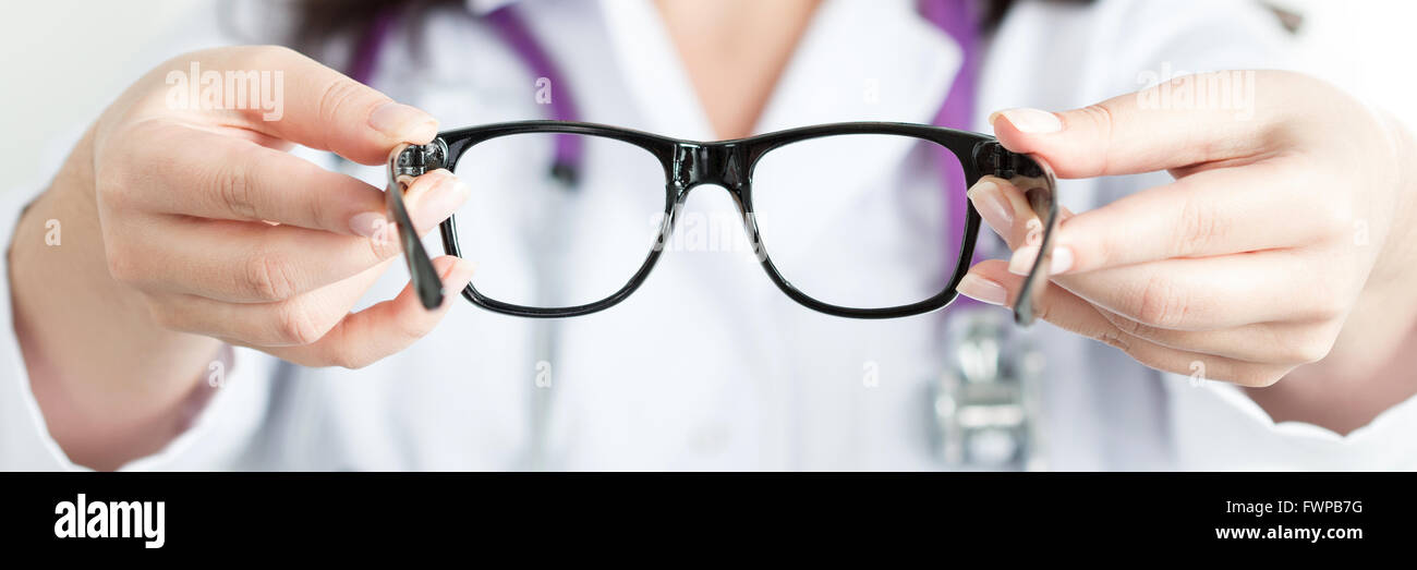 Female oculist doctor's hands giving a pair of black glasses. Good ...