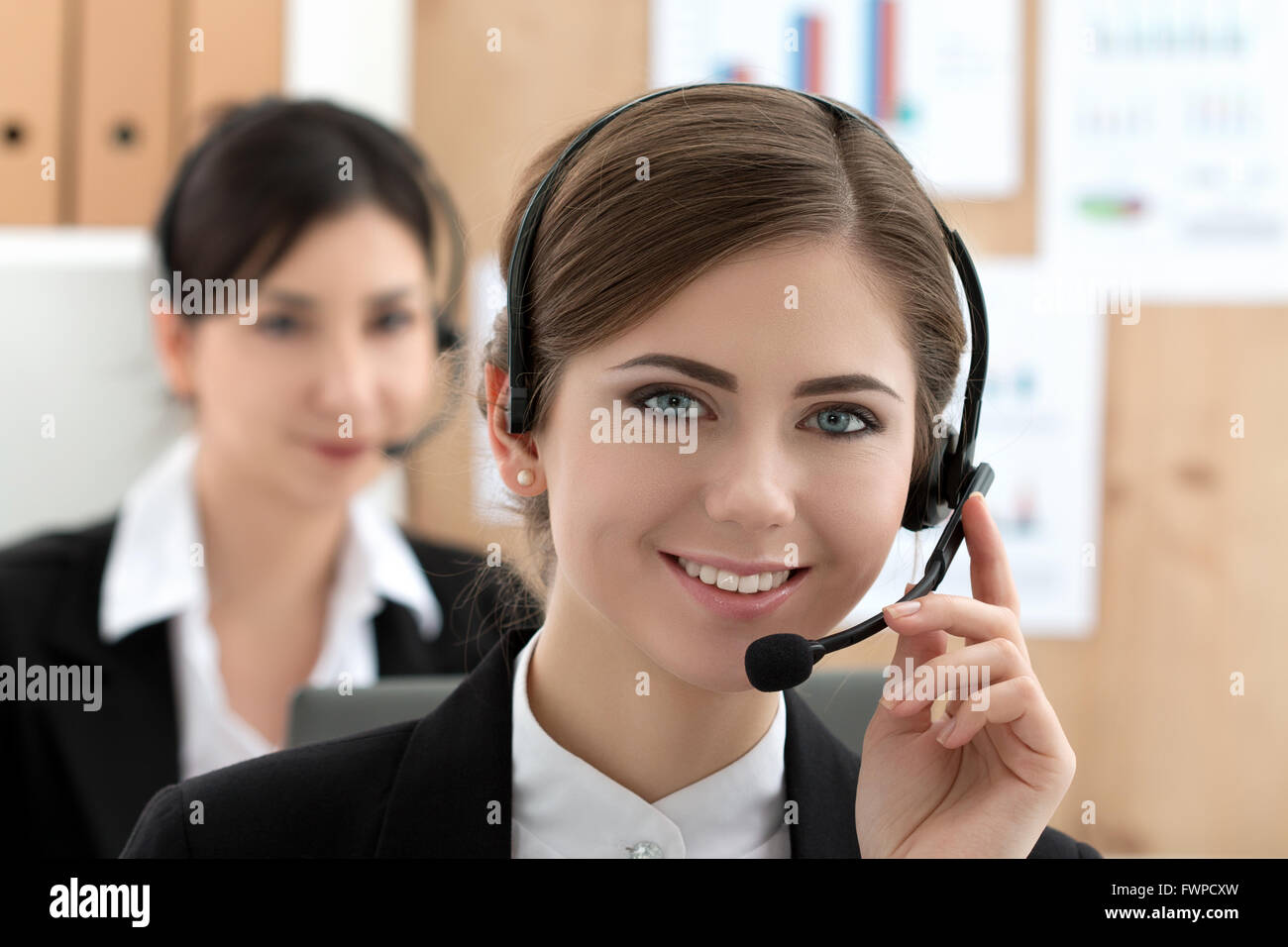 Portrait of call center worker accompanied by her team. Smiling ...