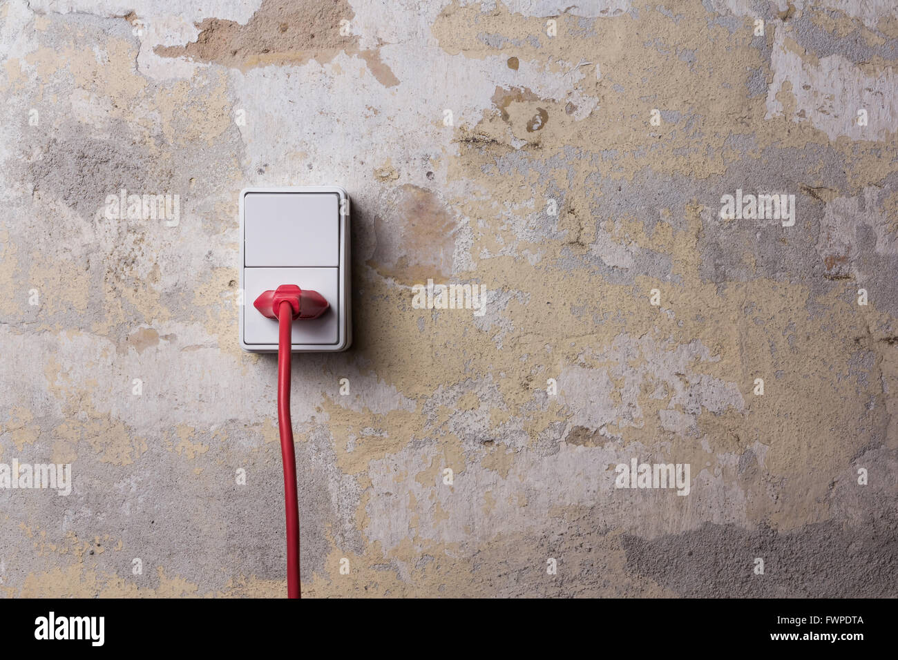 Red chord and plug in a white electrical socket fixed to a yellow ...