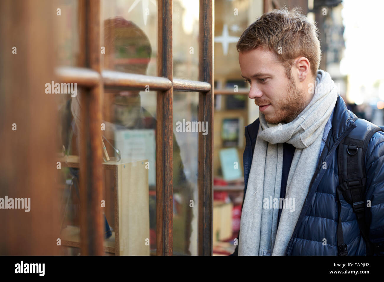 Young Man Looking In Shop Window In Town Centre Stock Photo - Alamy