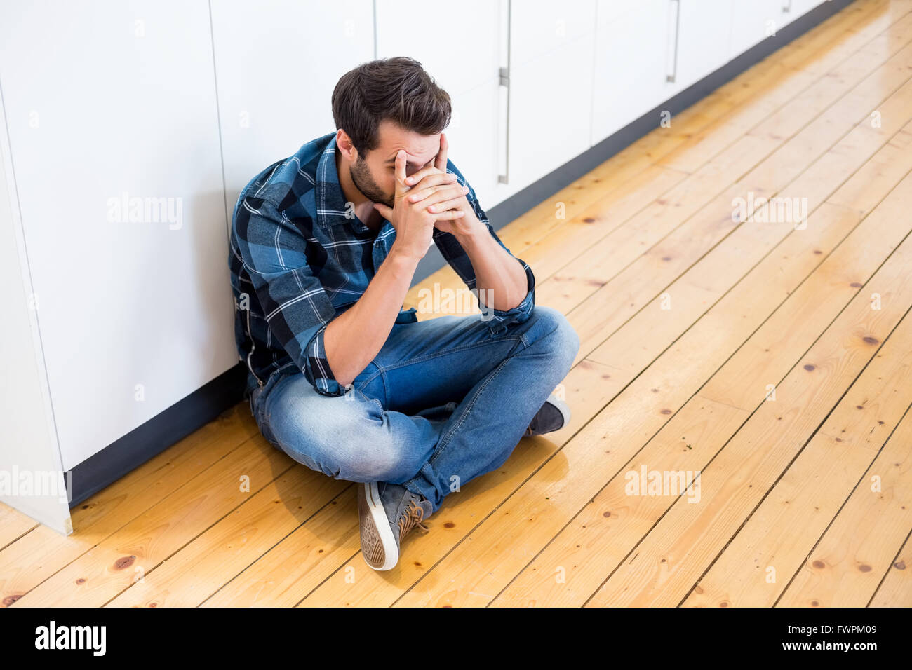 Tensed man sitting on wooden floor Stock Photo - Alamy