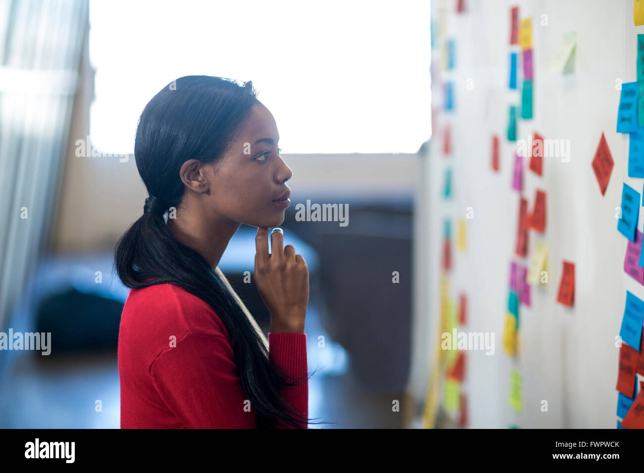 Young woman reading sticky notes on white board Stock Photo - Alamy