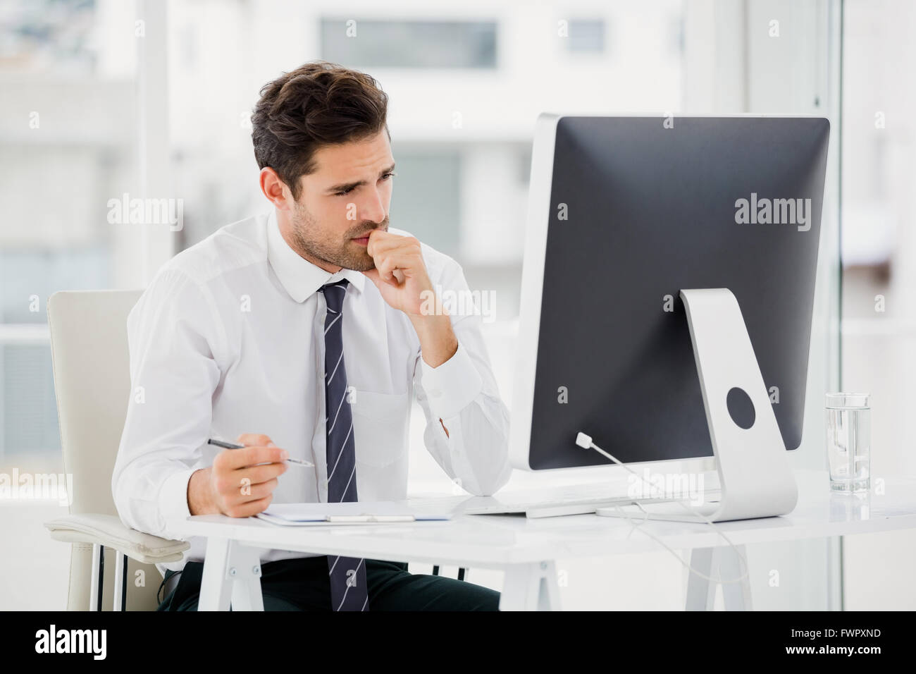 Businessman using computer and taking notes Stock Photo - Alamy