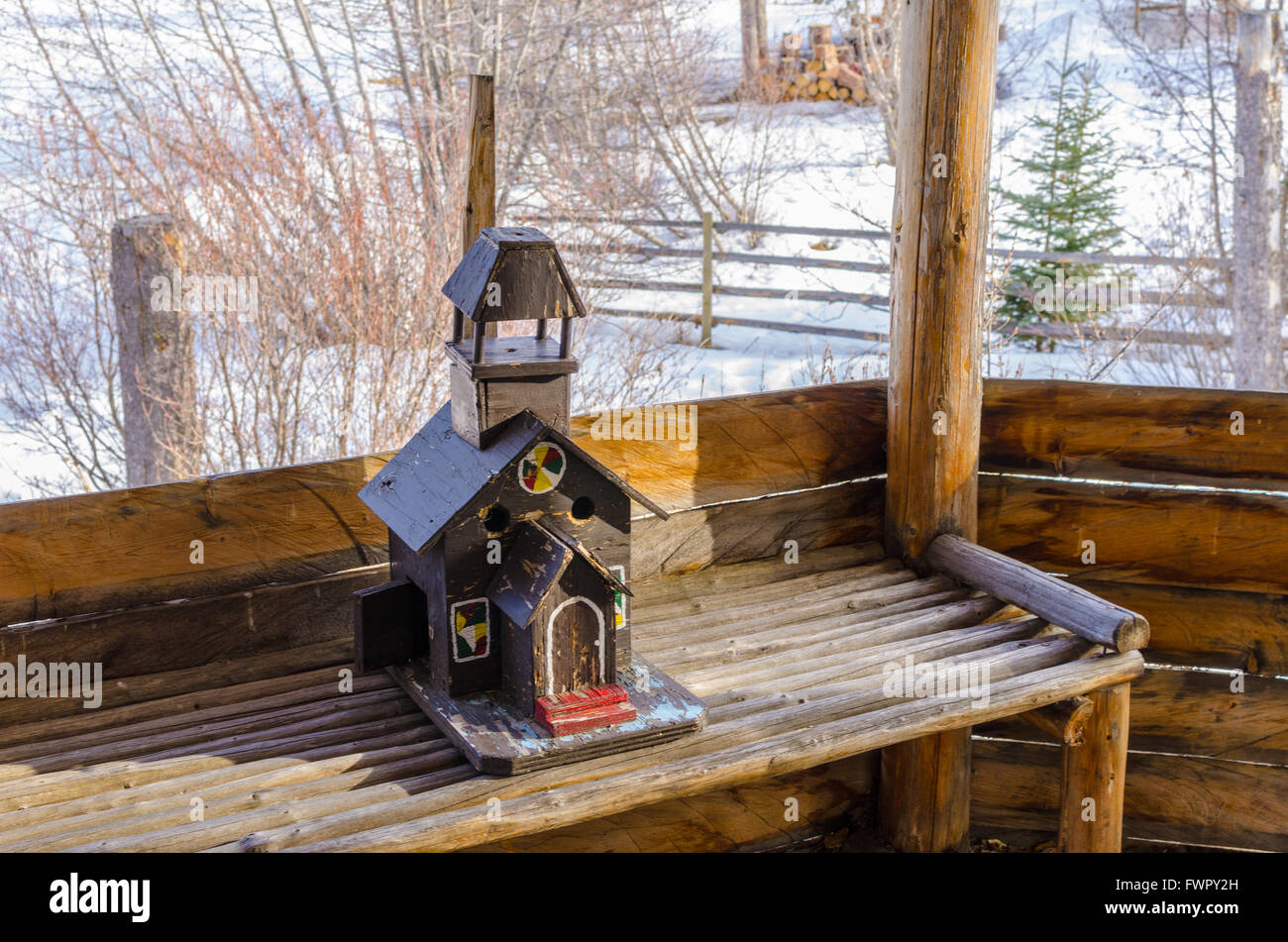 A wooden toy church sits on a bench in a gazebo during the winter at a ...