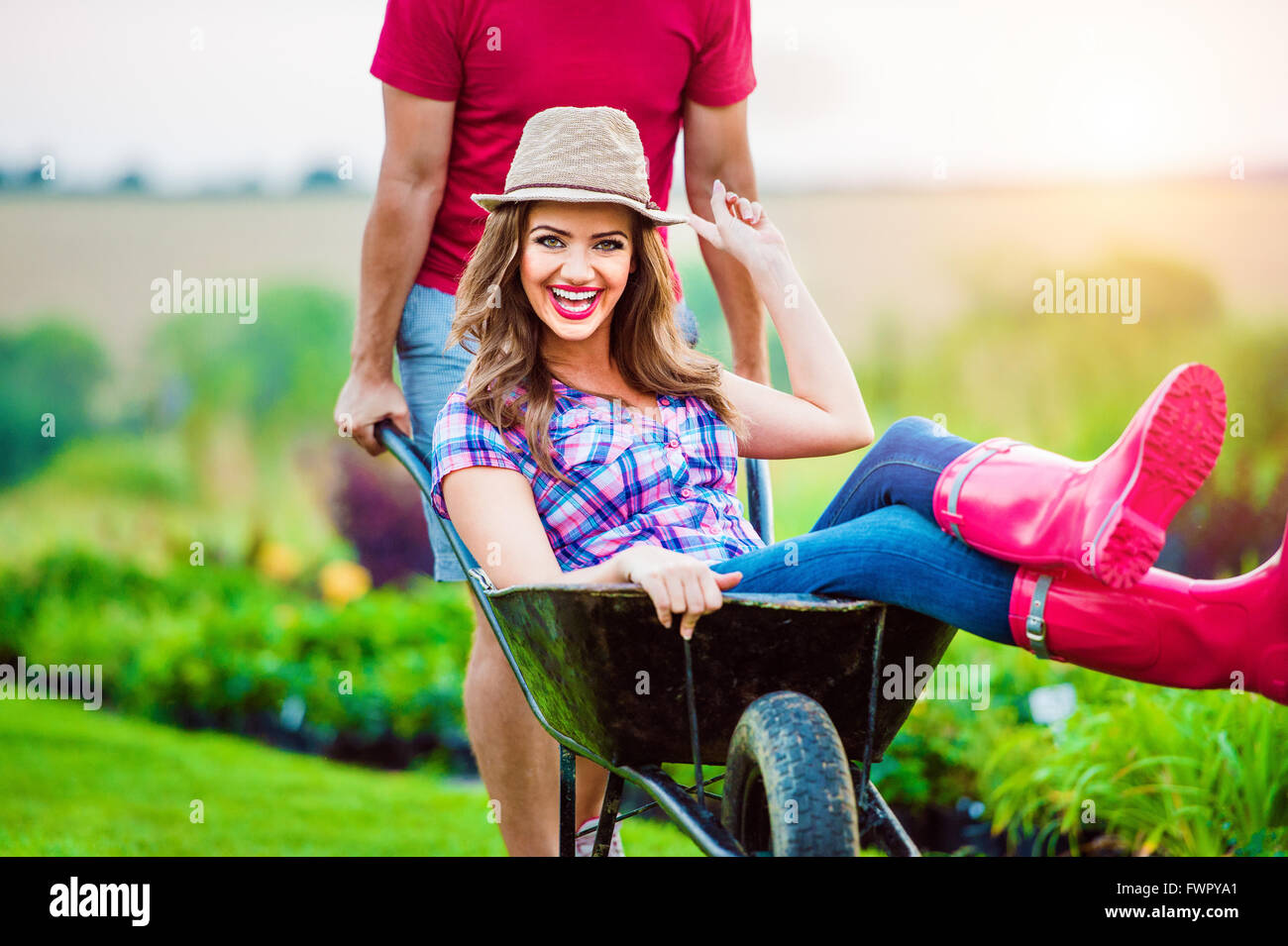Couple with man giving woman ride in wheelbarrow Stock Photo - Alamy