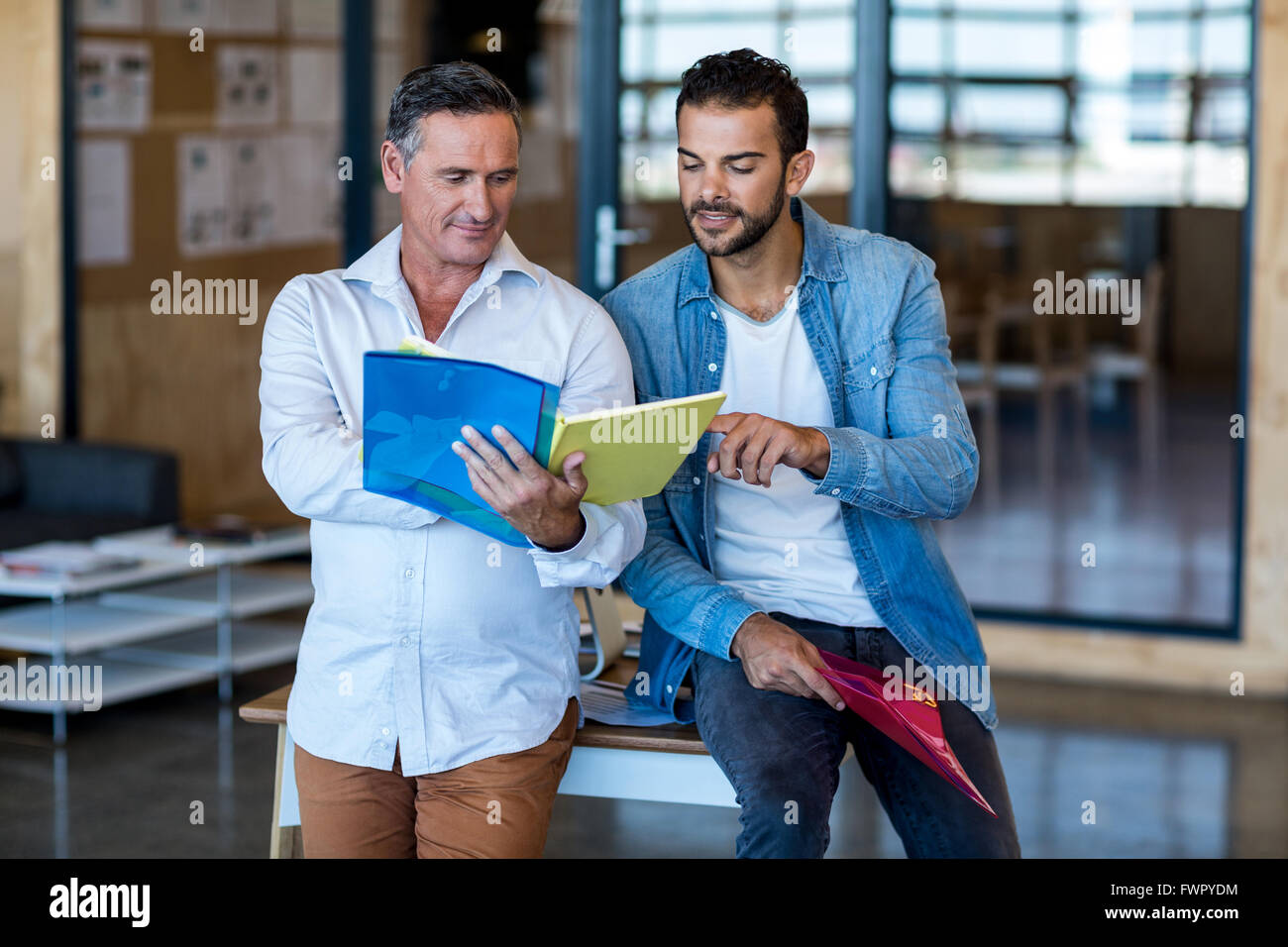 Colleagues looking at file Stock Photo - Alamy