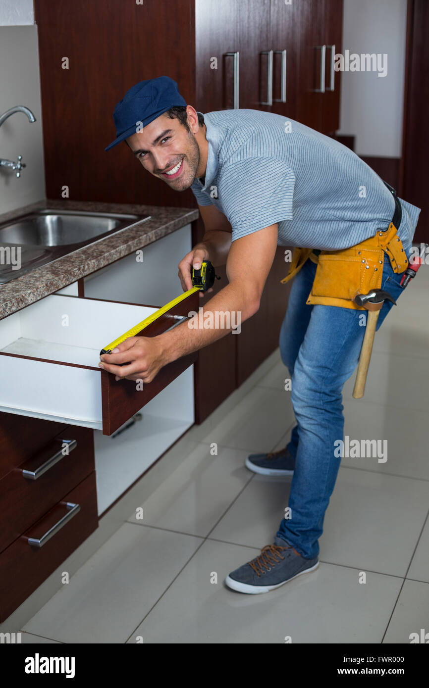 Full length portrait of man measuring drawer size Stock Photo - Alamy