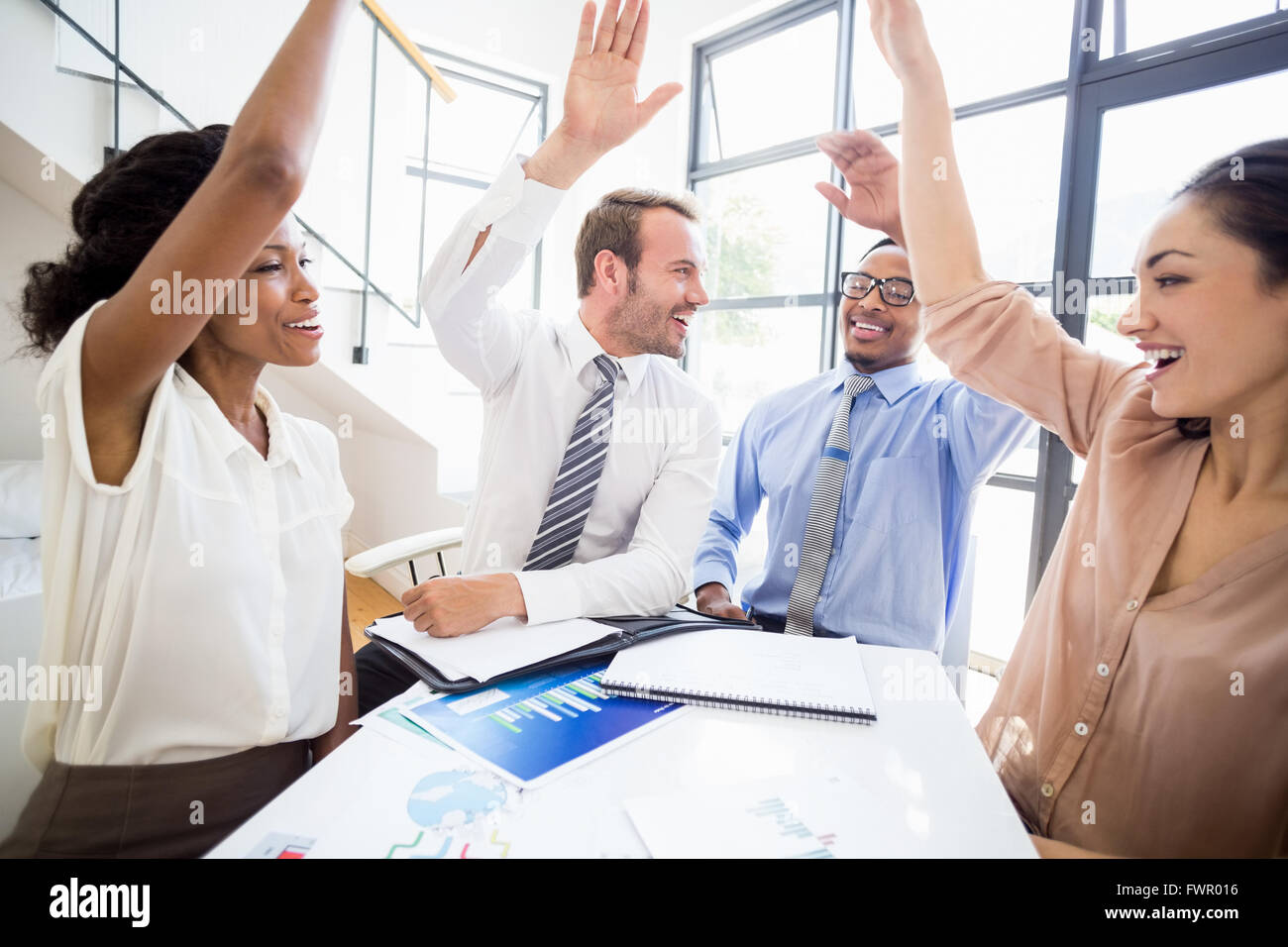 Happy businesspeople raising their hands during a meeting Stock Photo ...