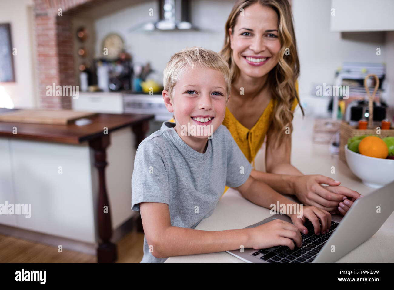 Portrait of mother and son using laptop in kitchen Stock Photo - Alamy