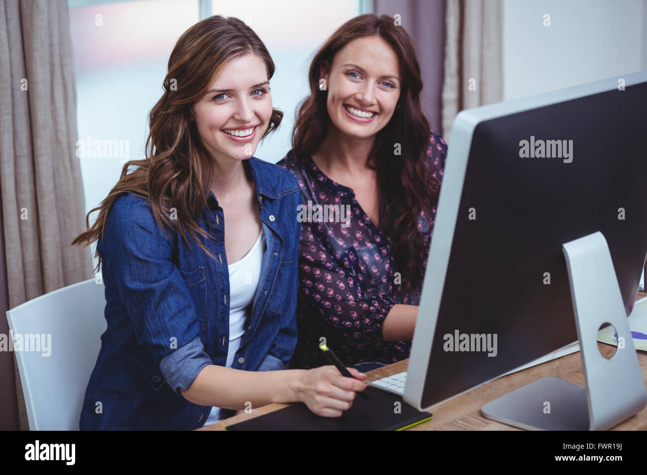 Portrait of two women sitting in front of computer Stock Photo - Alamy
