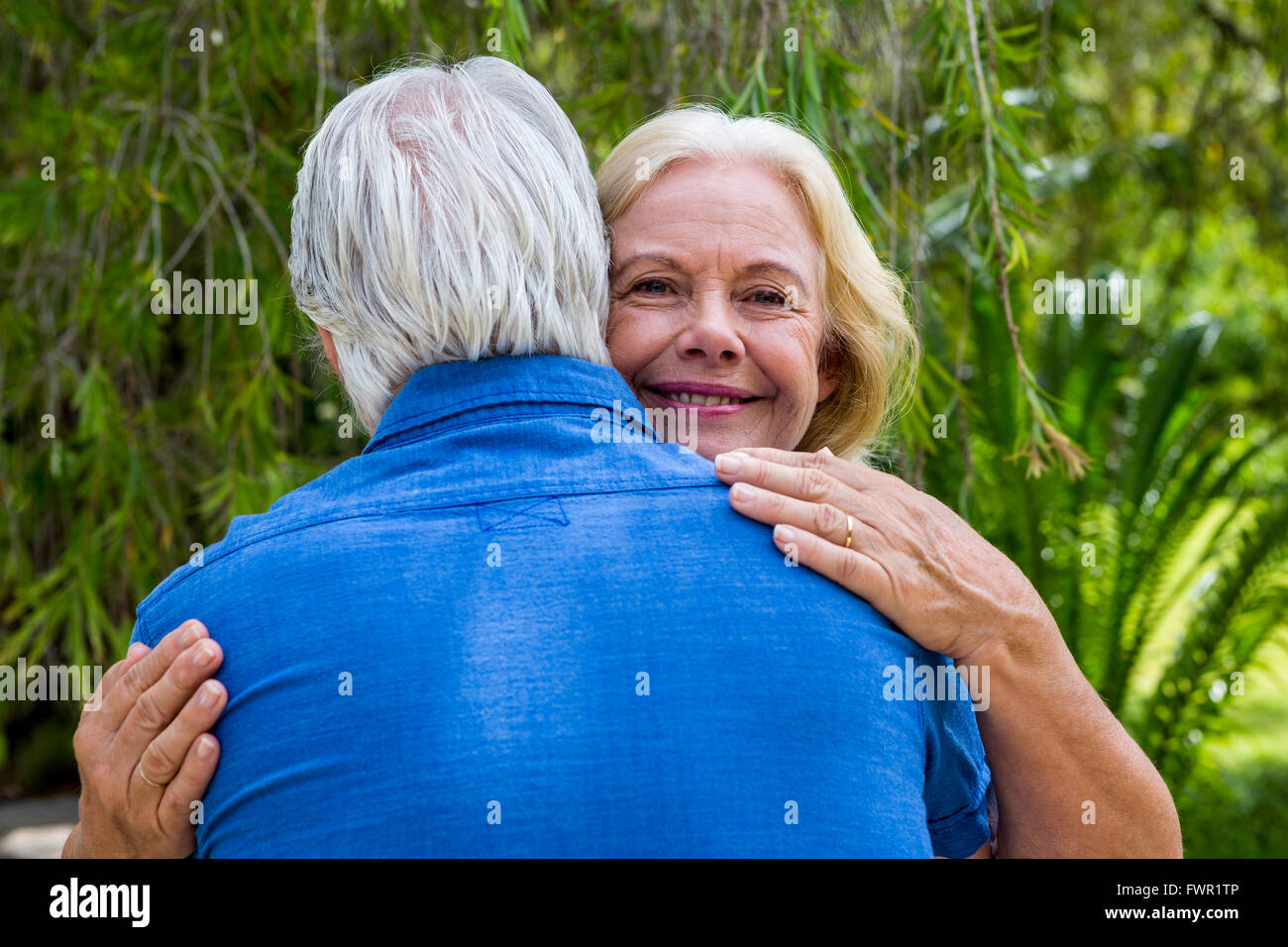 Senior woman hugging man against tree at park Stock Photo - Alamy