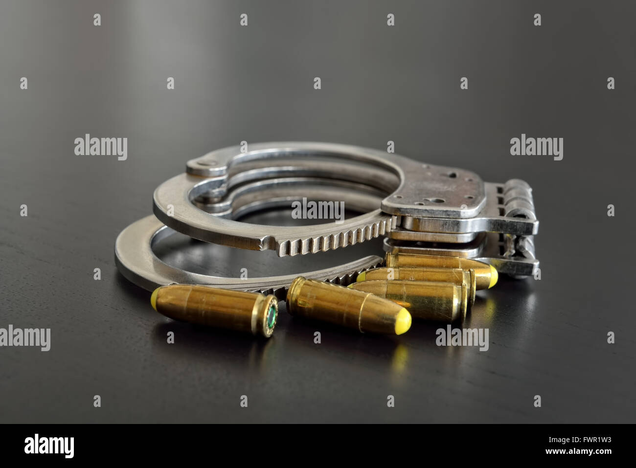Police handcuffs and pistol bullets on dark table closeup Stock Photo ...
