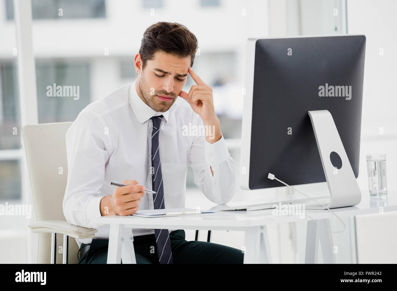 Businessman using computer and taking notes Stock Photo - Alamy