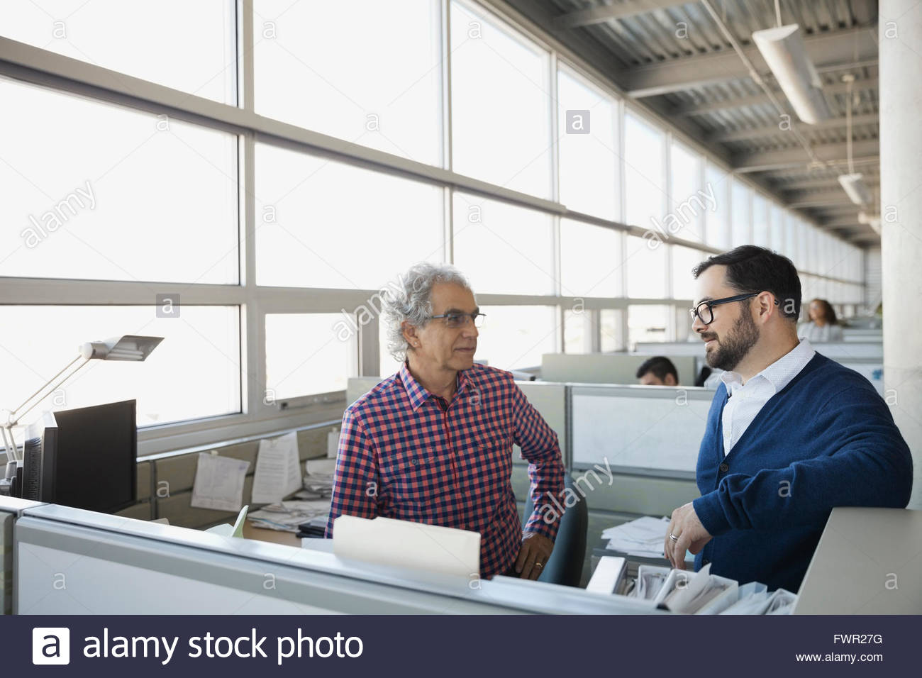 Businessmen discussing in office cubicle Stock Photo - Alamy